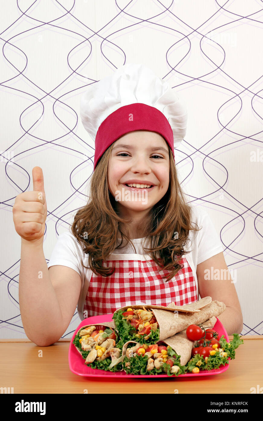 Happy little girl cook with burritos and thumb up Stock Photo - Alamy