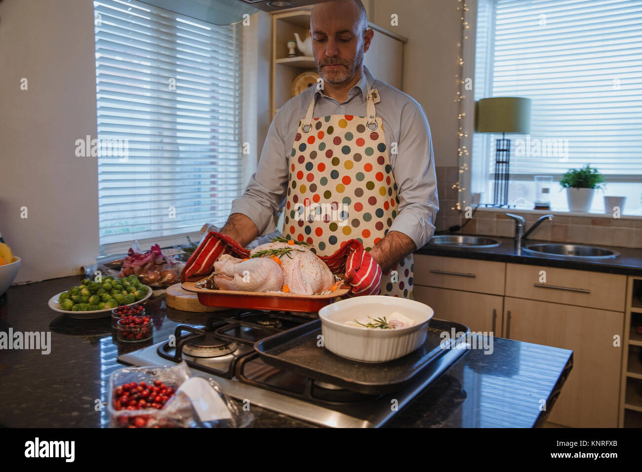 Mature man is preparing the Christmas dinner in the kitchen of his home ...