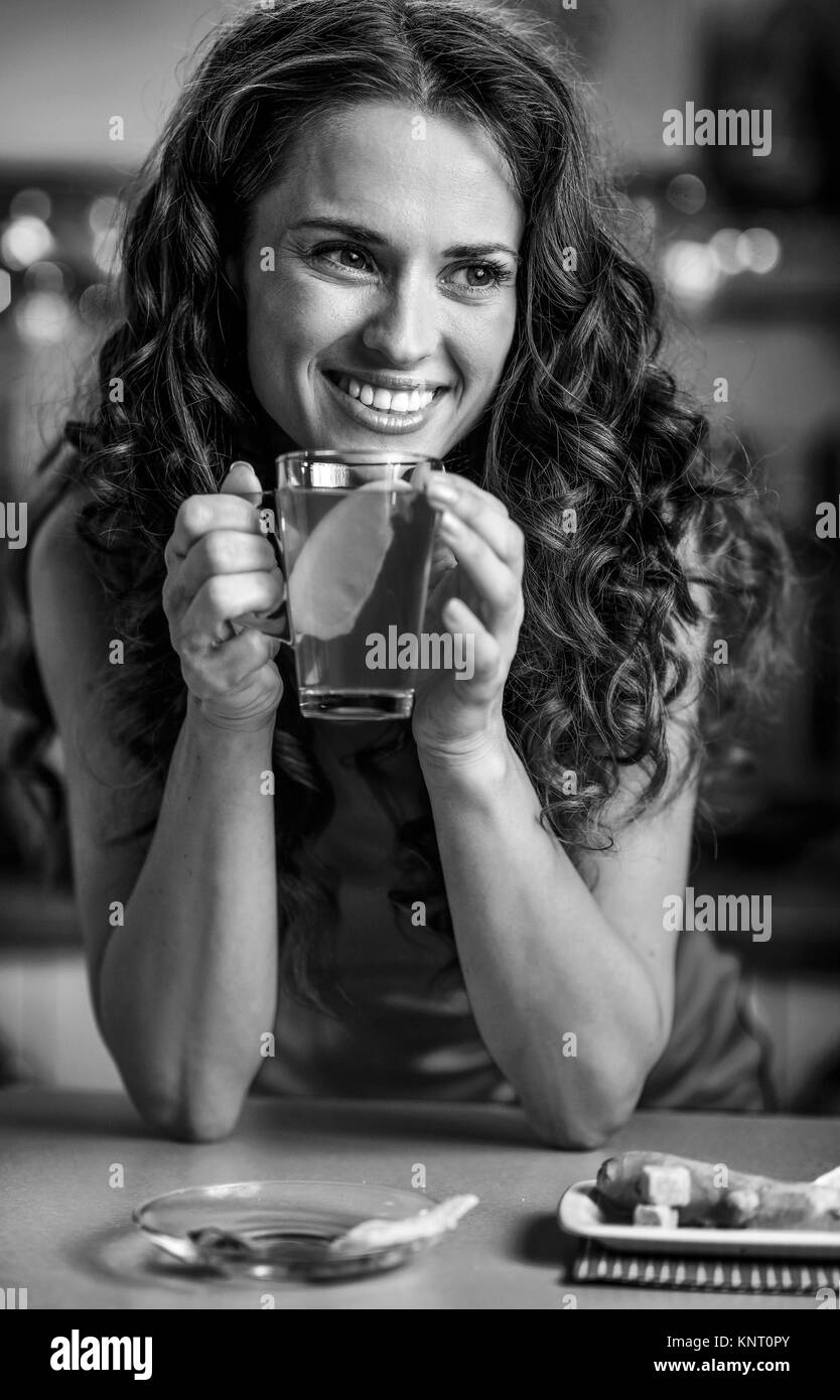 Happy young woman drinking ginger tea with lemon Stock Photo - Alamy