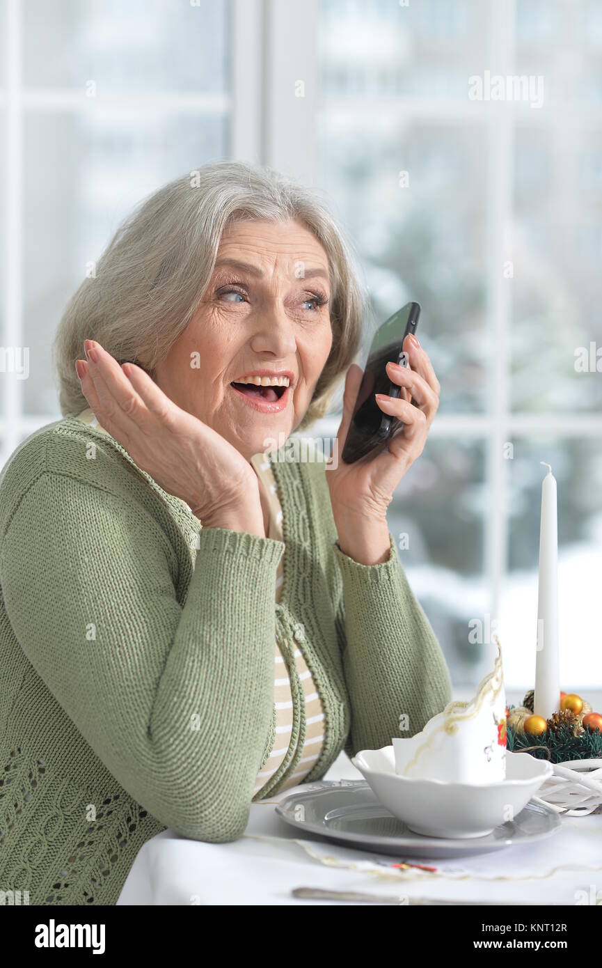 woman sitting at table with phone Stock Photo - Alamy