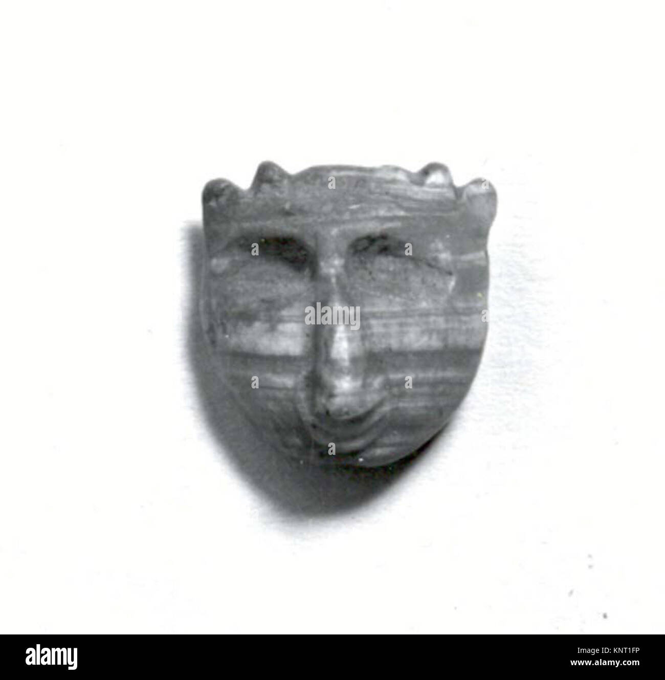 A demon-headed amulet from the MET collection, crafted from metal. The ...