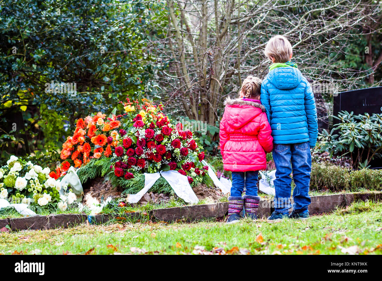 Little brother and sister standing at the grave of their parents in the ...