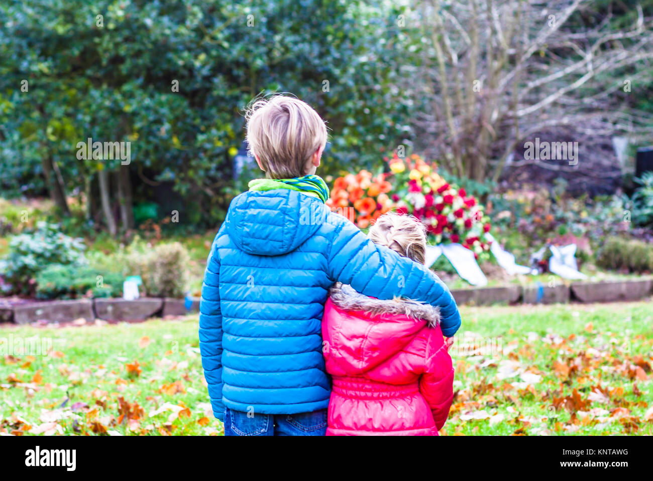 Little brother and sister standing at the grave of their parents in the ...