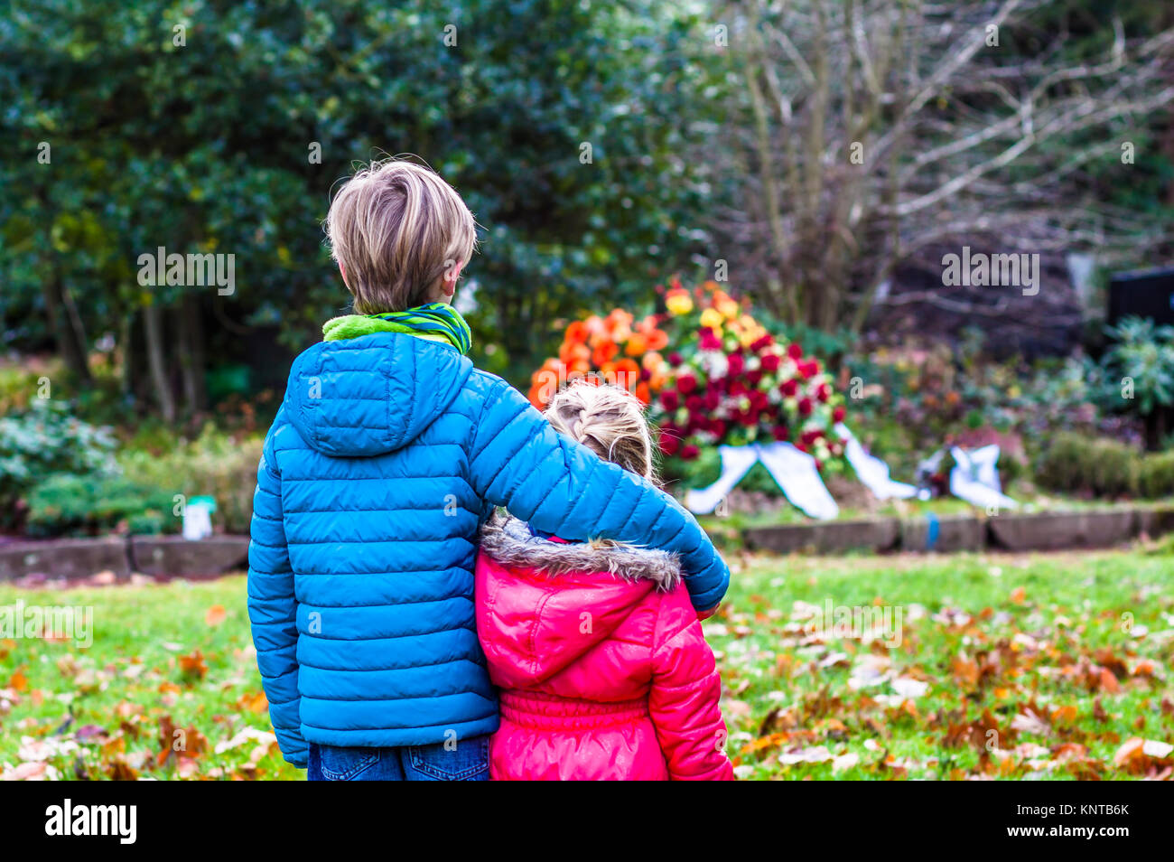 Little brother and sister standing at the grave of their parents in the ...