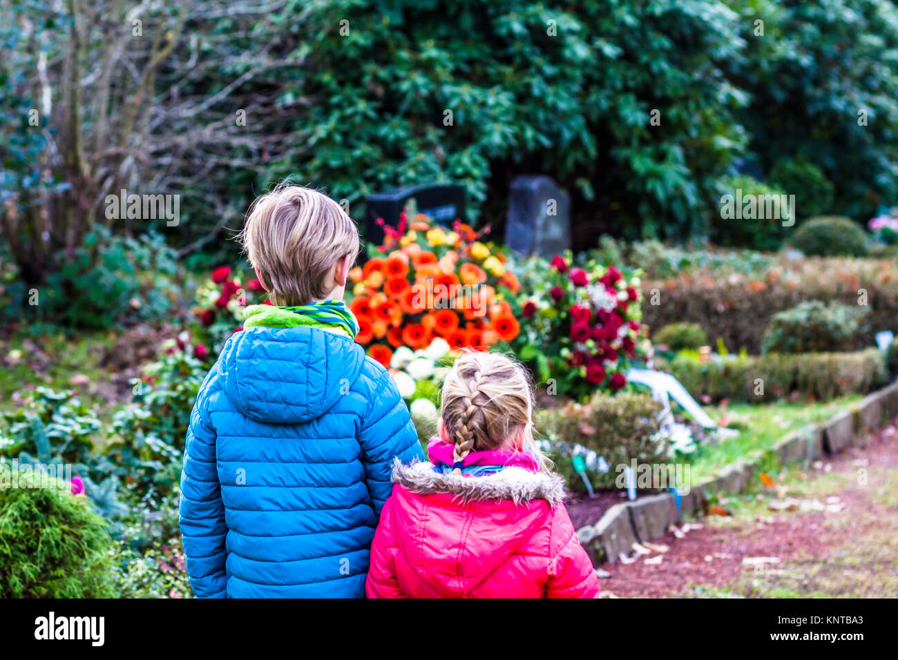 Little brother and sister standing at the grave of their parents in the ...