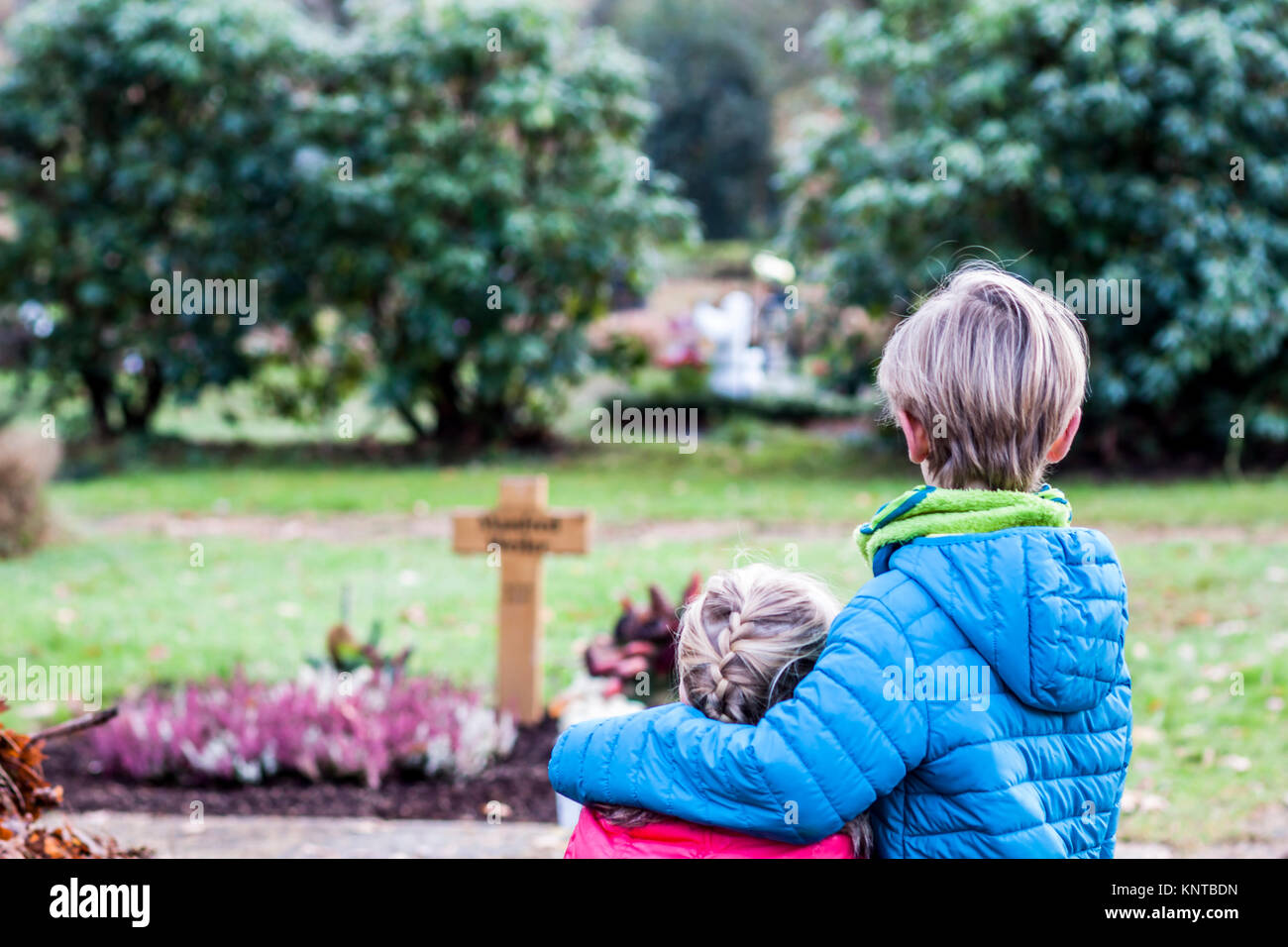 Little brother and sister standing at the grave of their parents in the ...