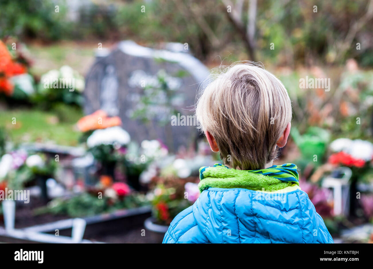 Little boy standing at the grave of his parents in the graveyard Stock ...