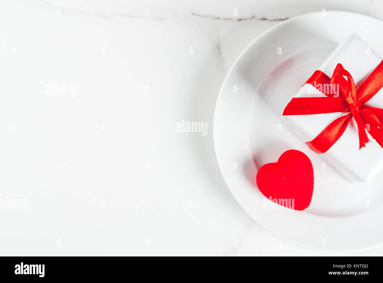 Valentine's day table setting with plate, gift box and red heart, on ...