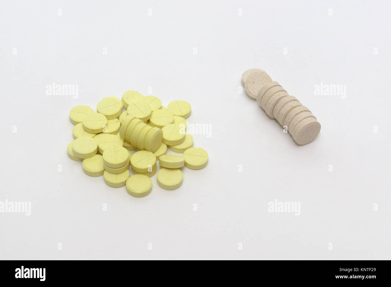 handful of yellow tablets with parting lines and neat stack of beige ...