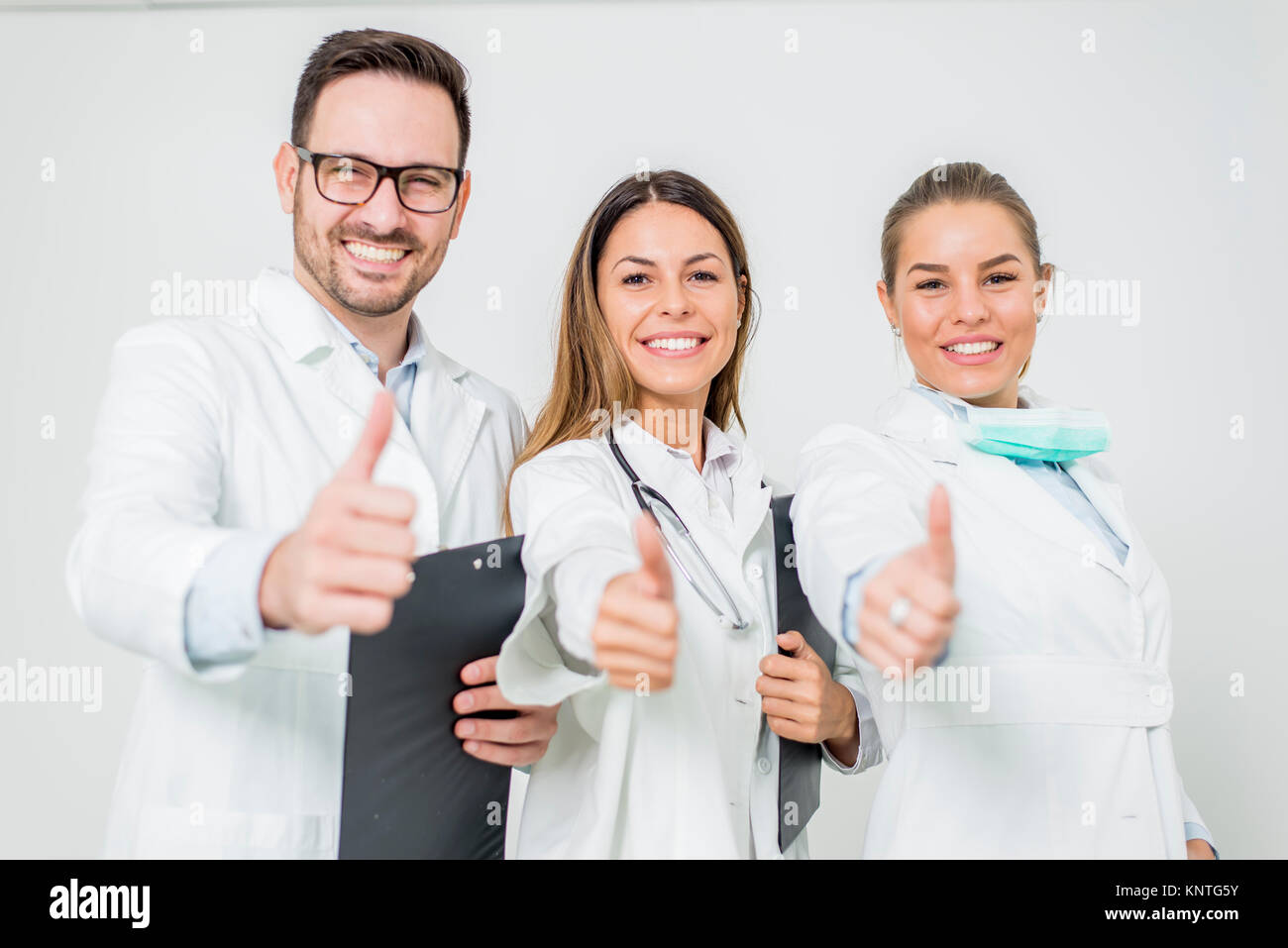 Friendly group of doctors with thumbs up by the white wall Stock Photo ...