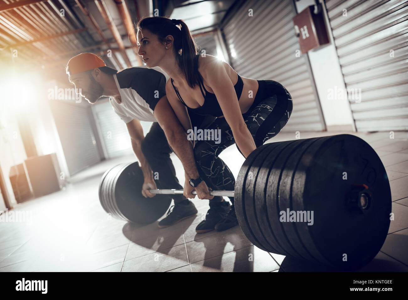 Young muscular couple ready to deadlift exercise at the garage gym ...