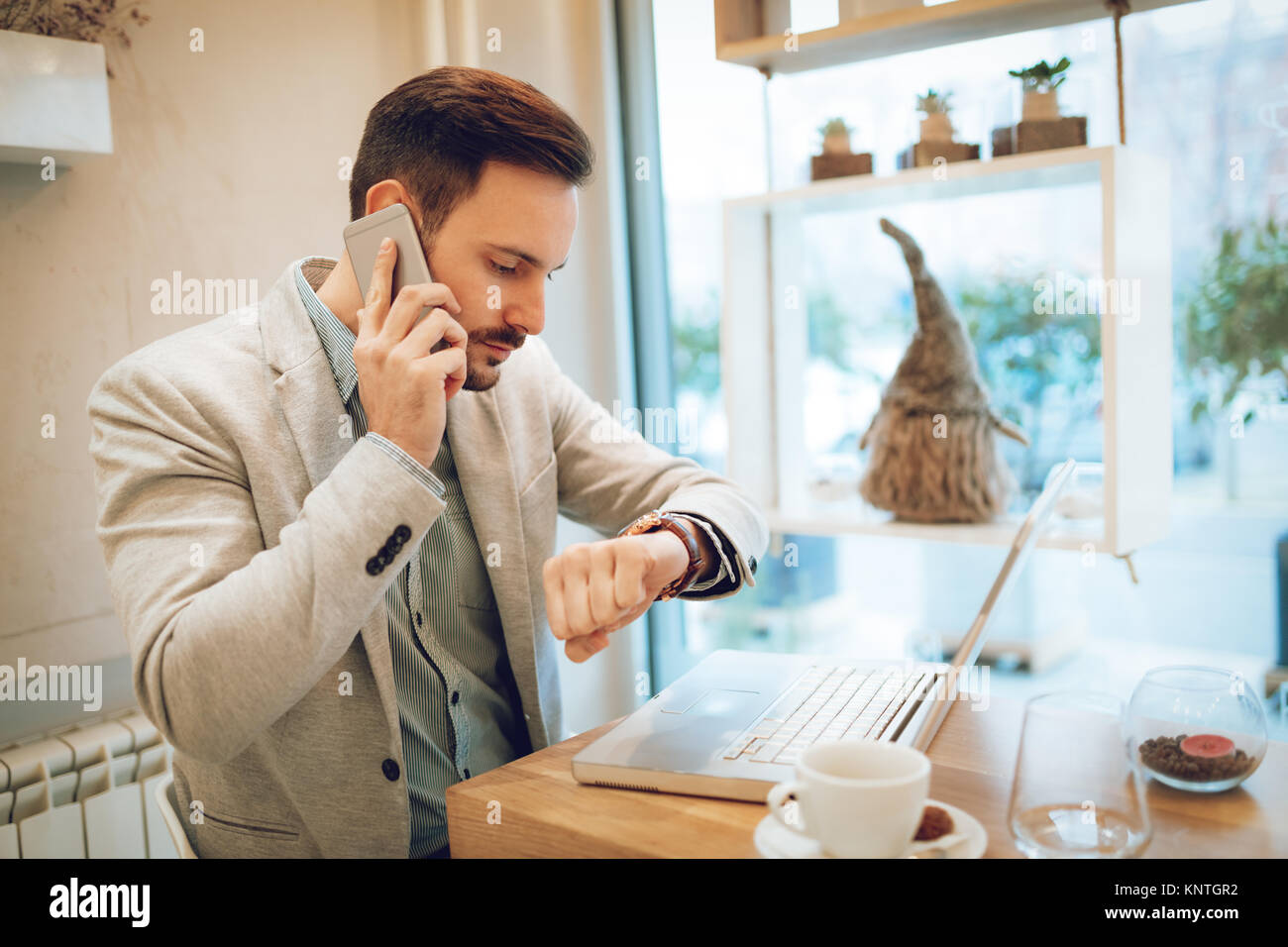 Young overworked businessman on a break in a cafe. He is looking at ...