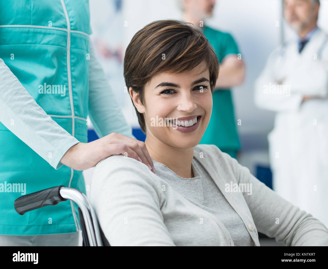 Smiling young disabled patient at the hospital, a nurse is pushing her ...