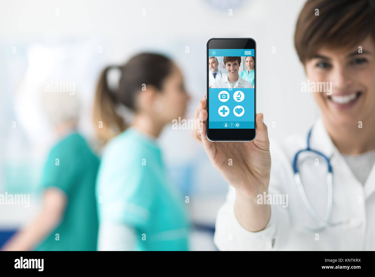 Smiling confident female doctor holding a touch screen smartphone and ...