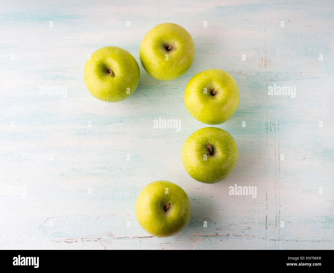 Green apples forming question mark on turquoise white table. Flat lay ...
