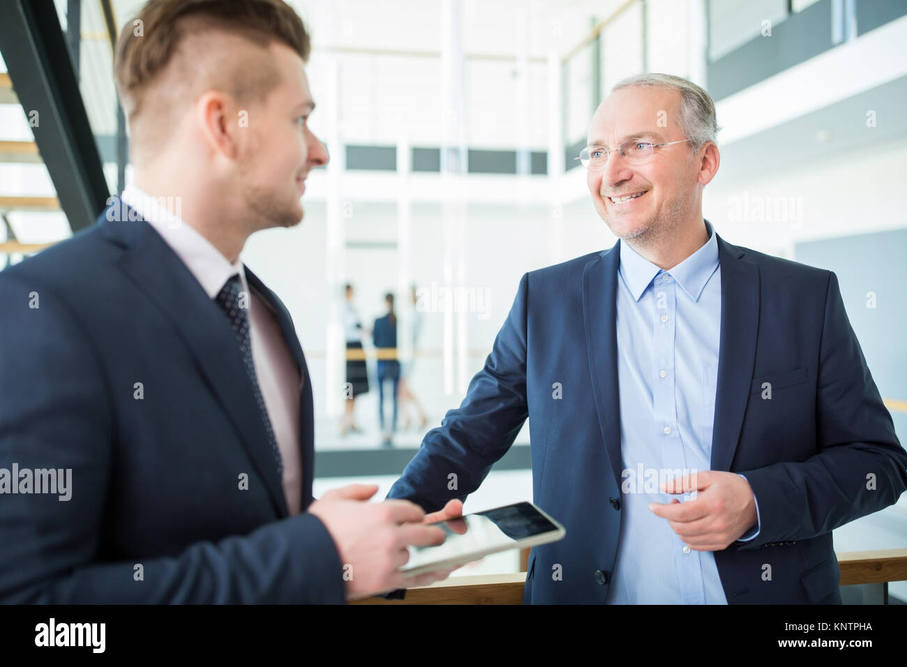 Confident businessman smiling while communicating with colleague in ...