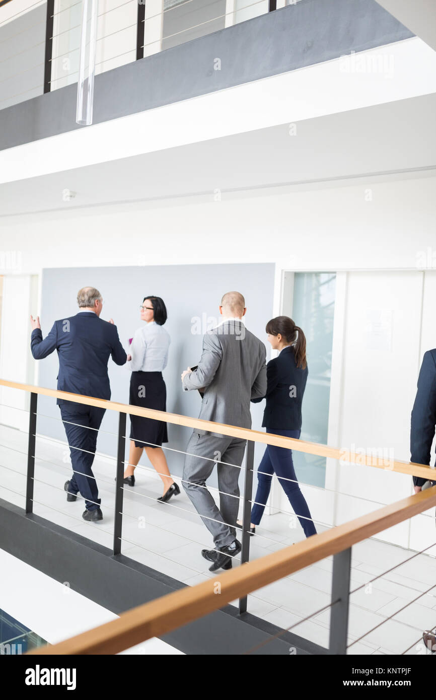 Full length of business people planning while walking by railing on ...