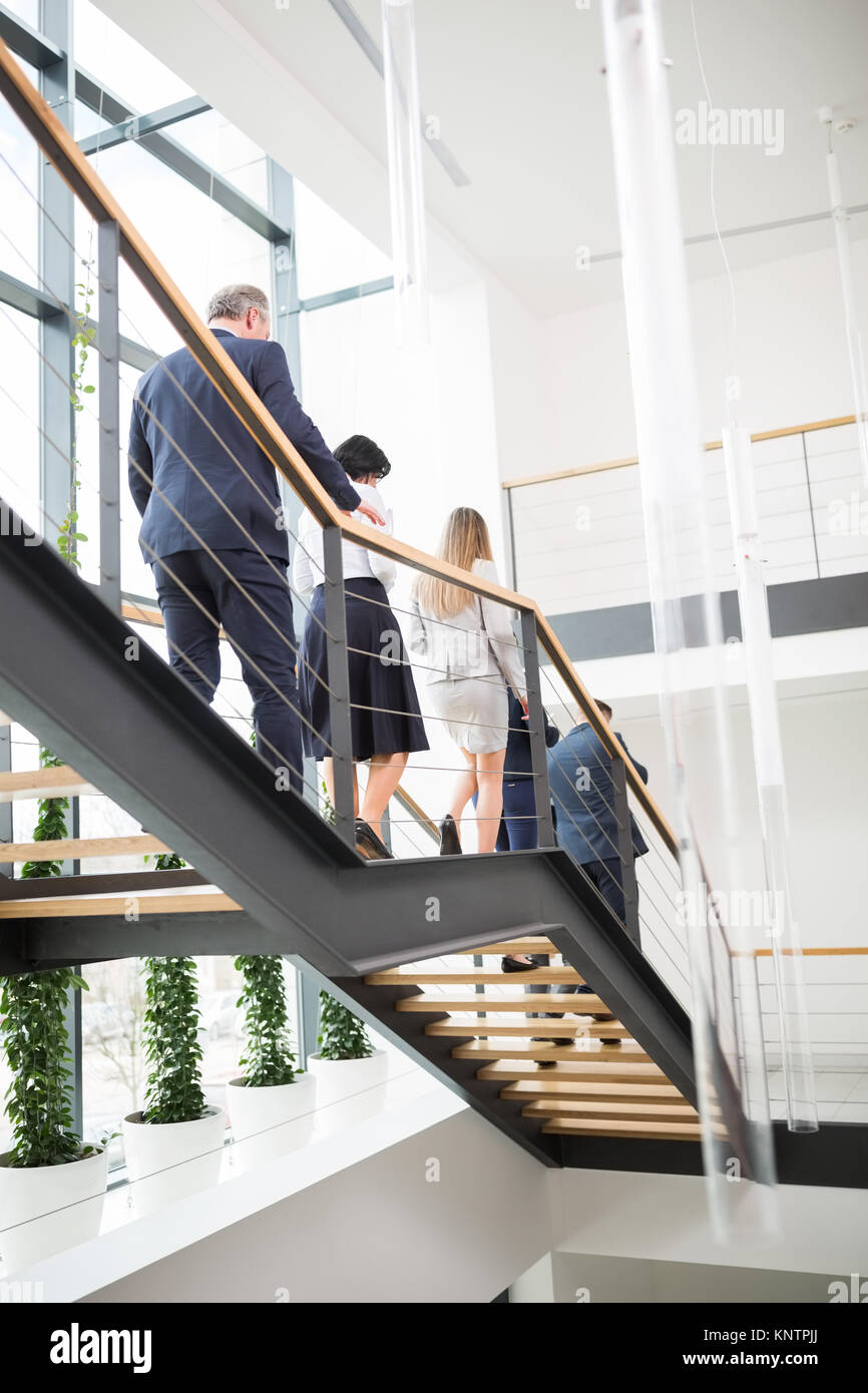 Rear view of business people walking downstairs in modern office Stock ...