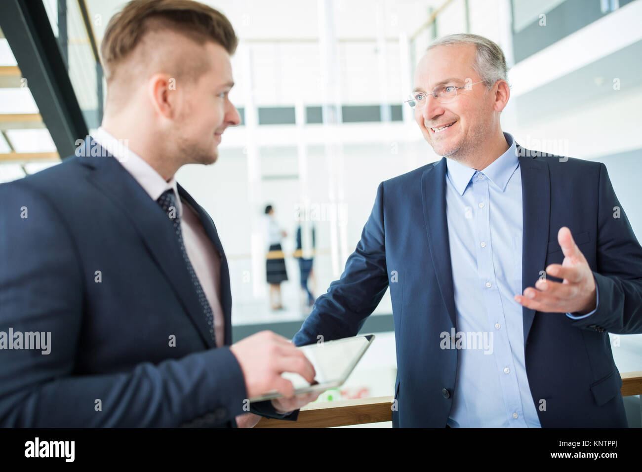 Confident businessman smiling while talking to colleague in office ...