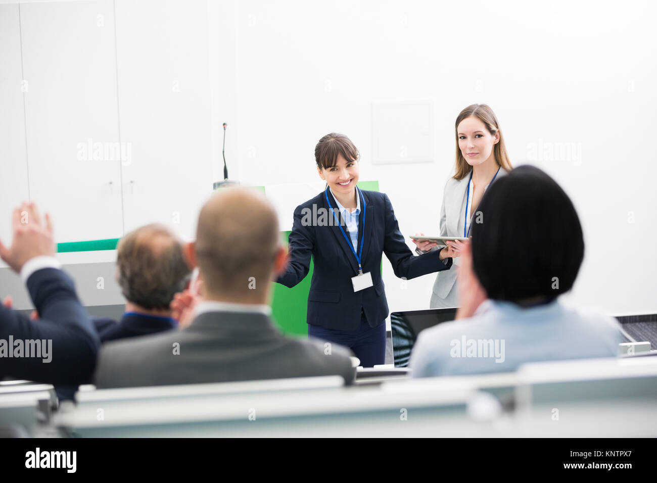 Smiling businesswoman standing by colleague while giving presentation ...