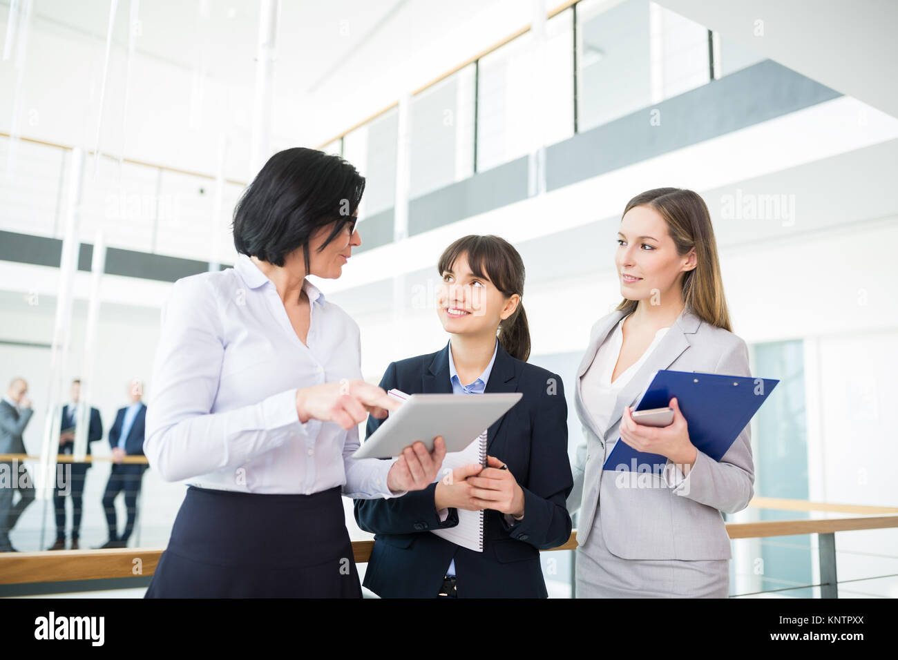 Mature female professional explaining project to colleagues on tablet ...