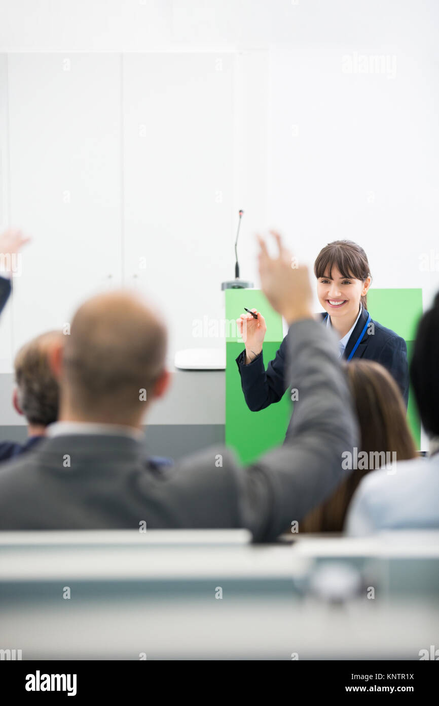 Smiling businesswoman asking questions to colleagues while giving ...