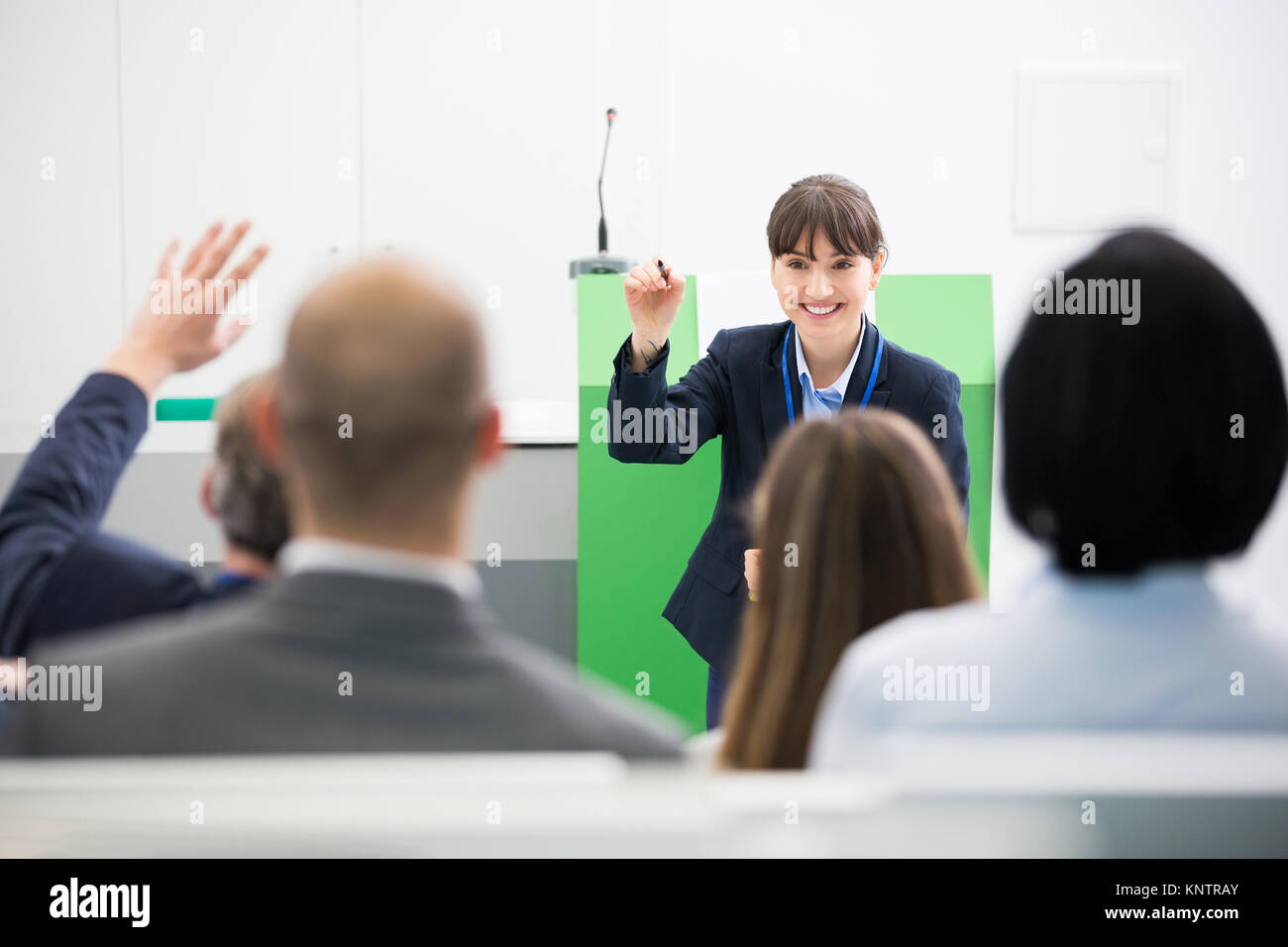 Confident businesswoman asking questions to colleagues while giving ...