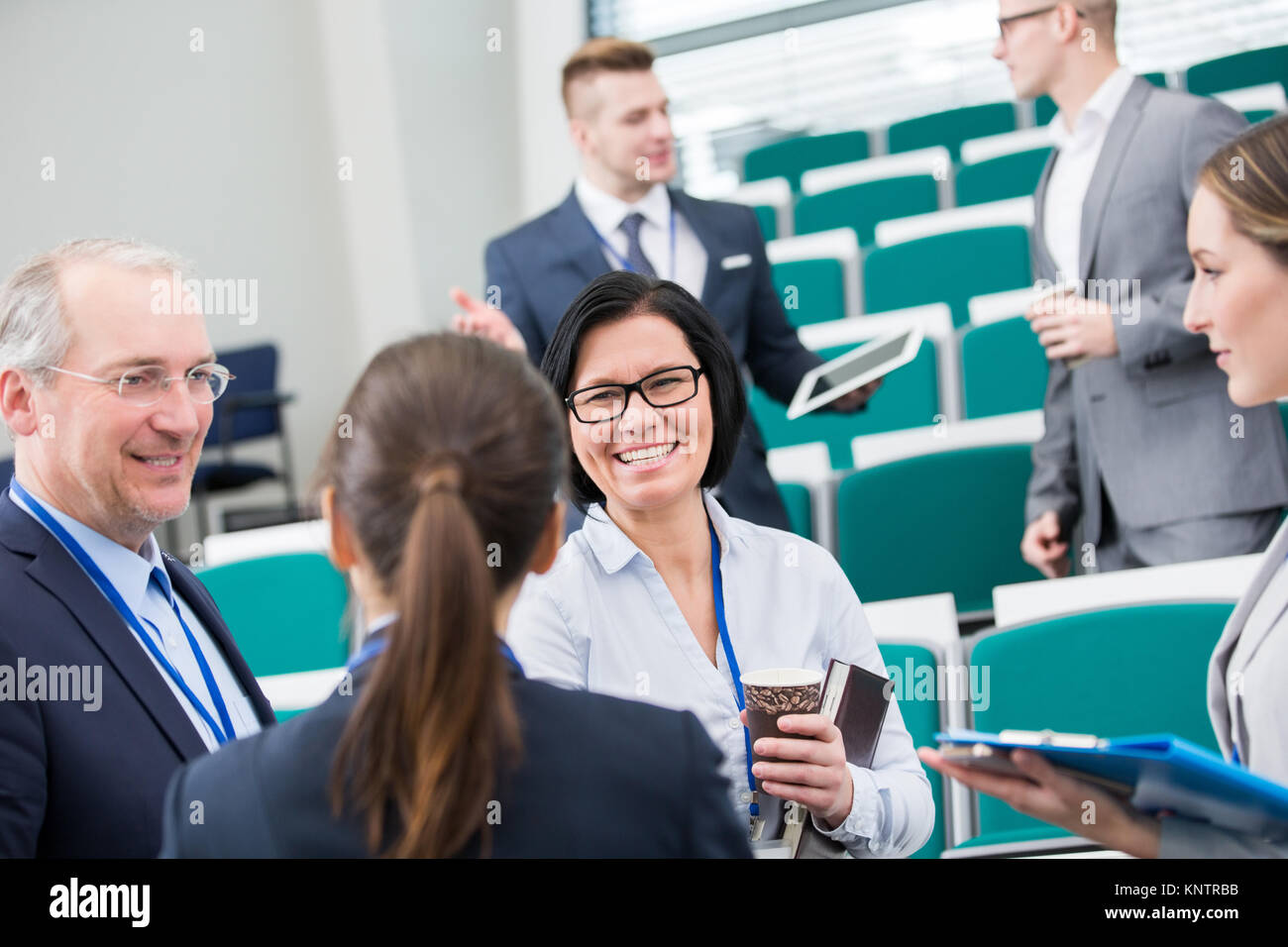 Mature businesswoman smiling while communicating with colleagues in ...