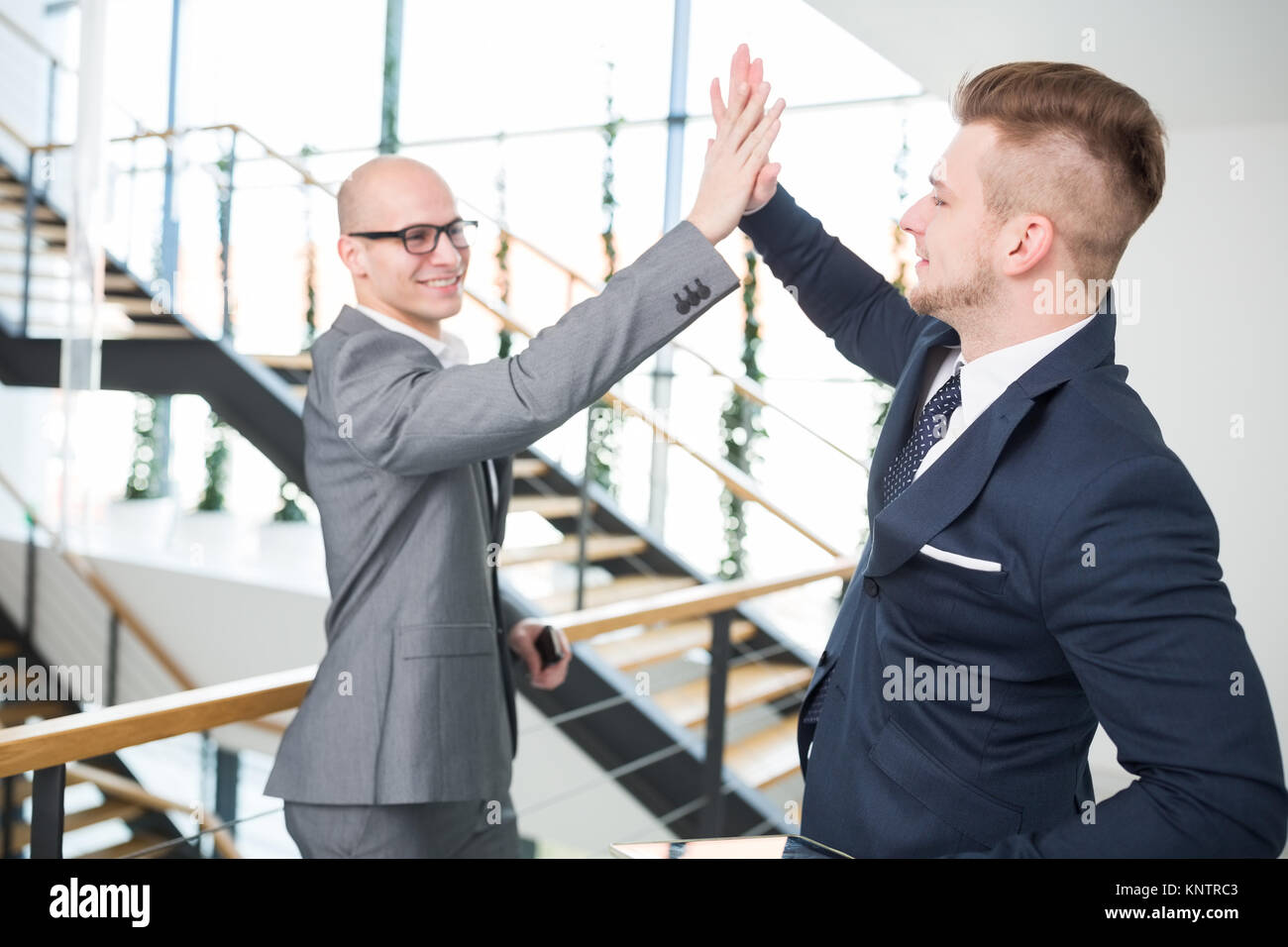Successful young businessmen giving highfive in office Stock Photo - Alamy