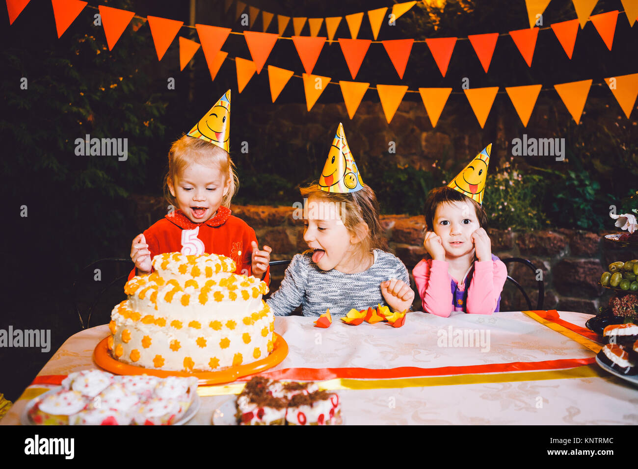 Children's birthday party. Three cheerful children girls eating cake ...