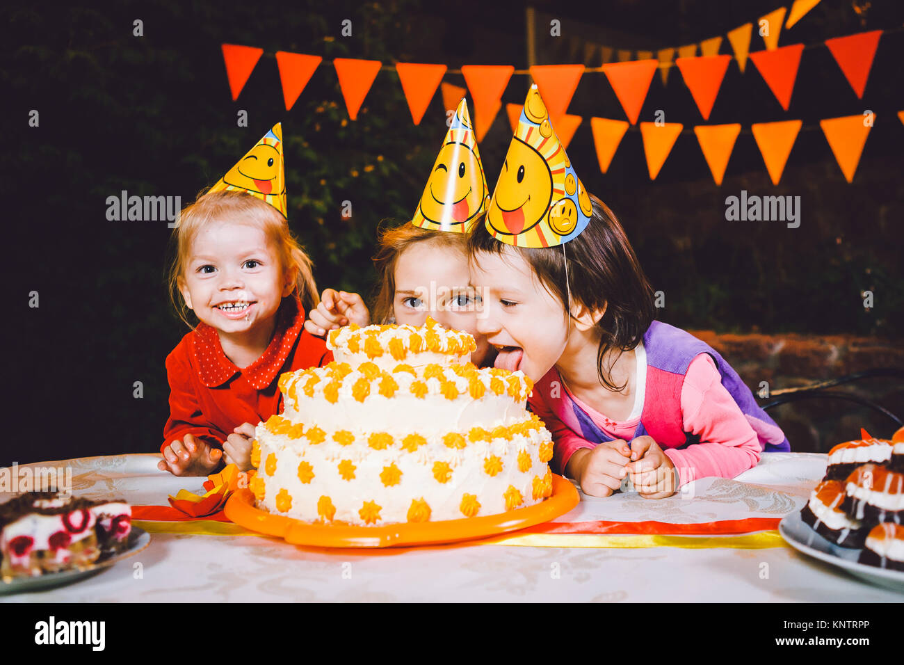 Children's birthday party. Three cheerful children girls eating cake ...