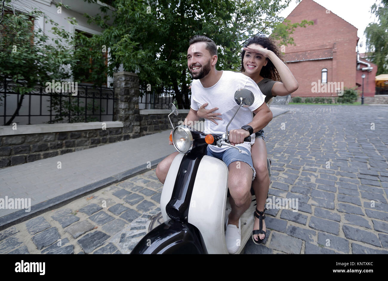 Young couple riding motor scooter in city Stock Photo - Alamy