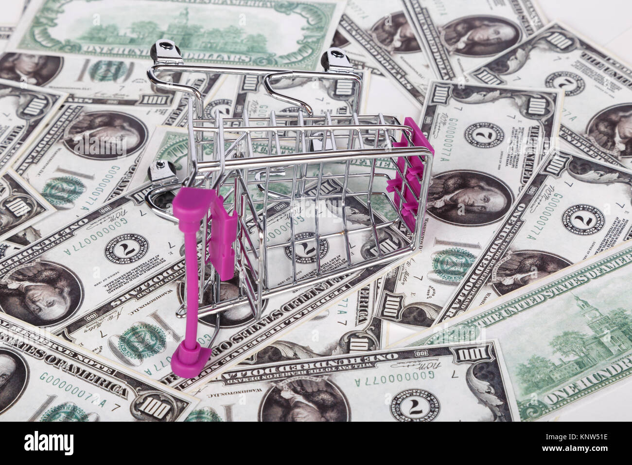 Stack of Dollar banknotes with shopping cart in money consuming concept ...