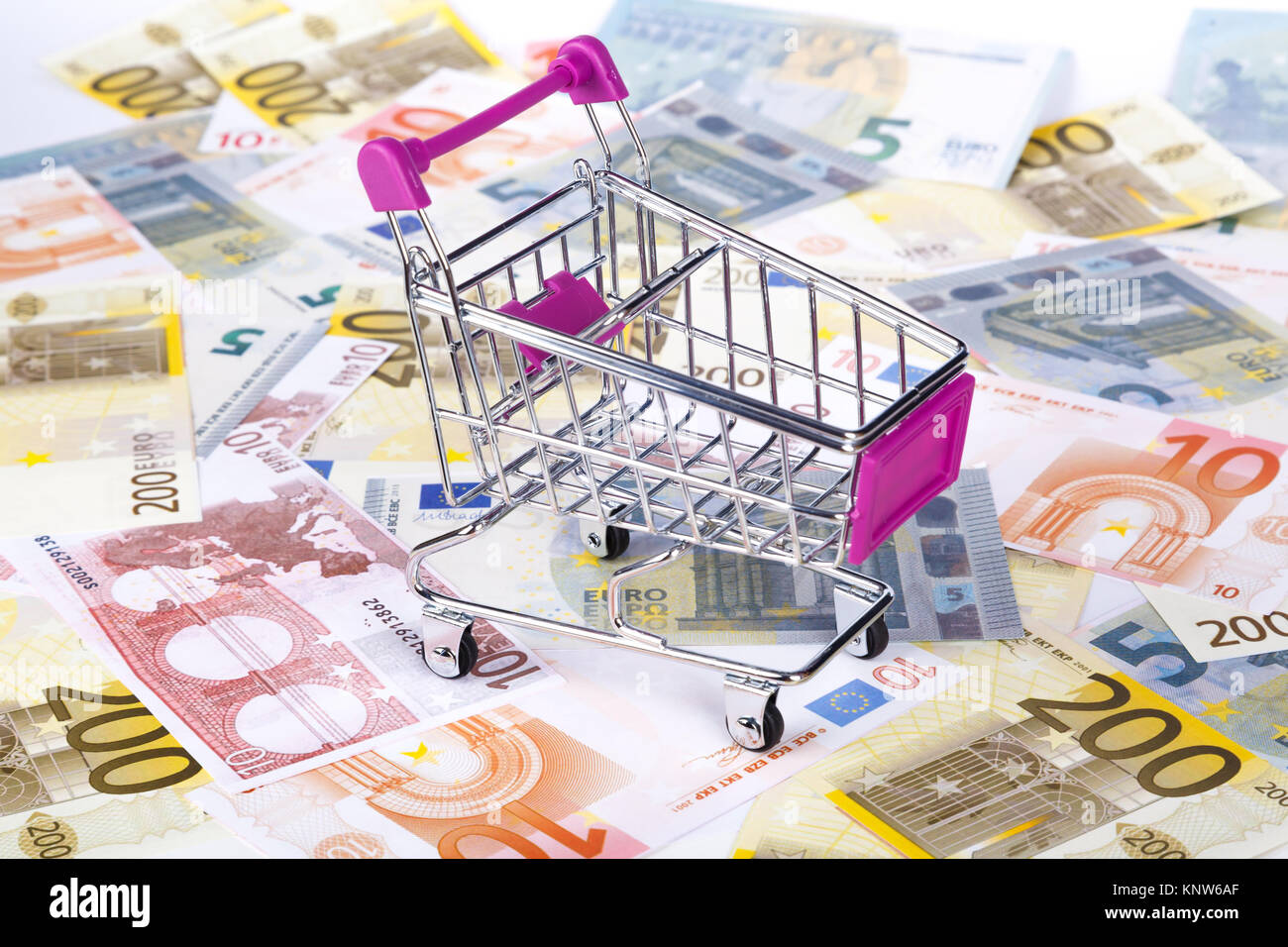 Stack of Euro banknotes with shopping cart in money consuming concept ...