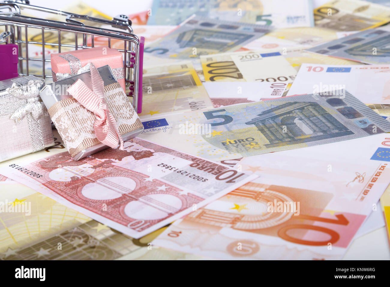 Stack of Euro banknotes with shopping cart and gift boxes in money ...