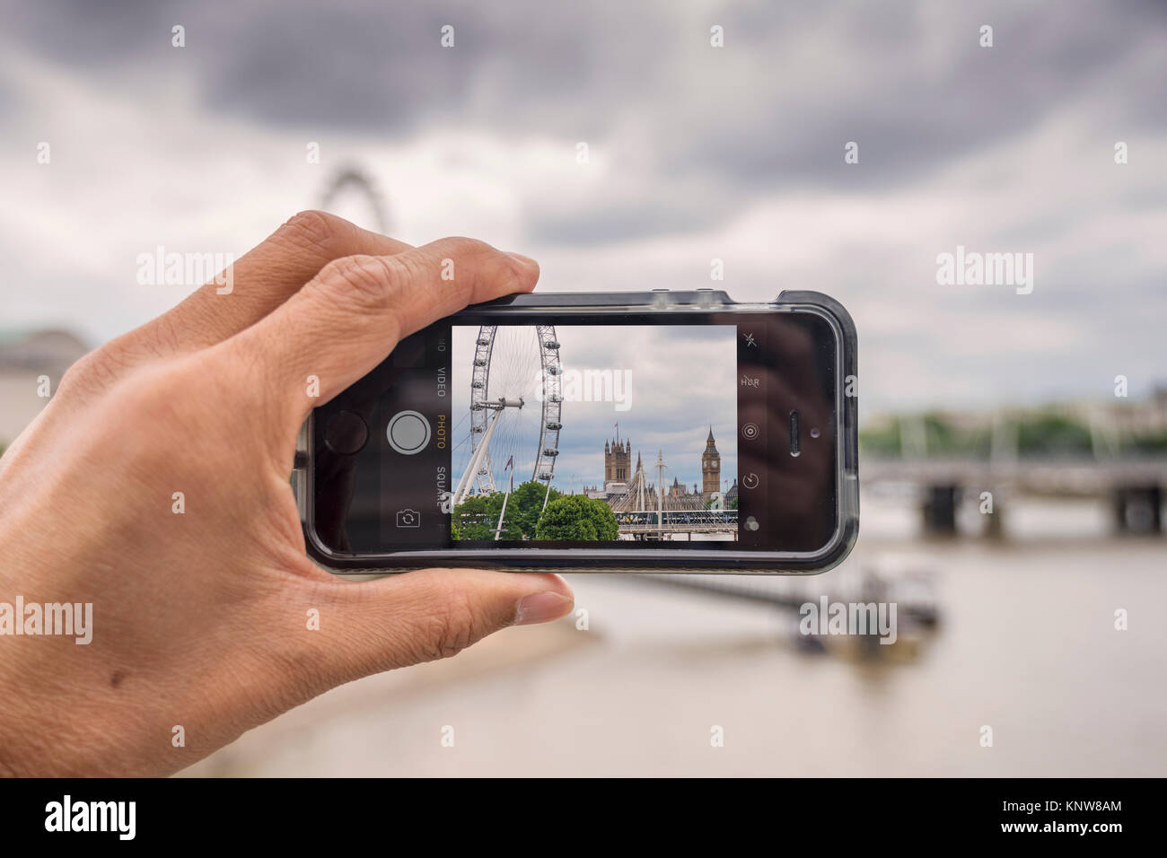 A male taking a photo of London's skyline with his smartphone, London ...