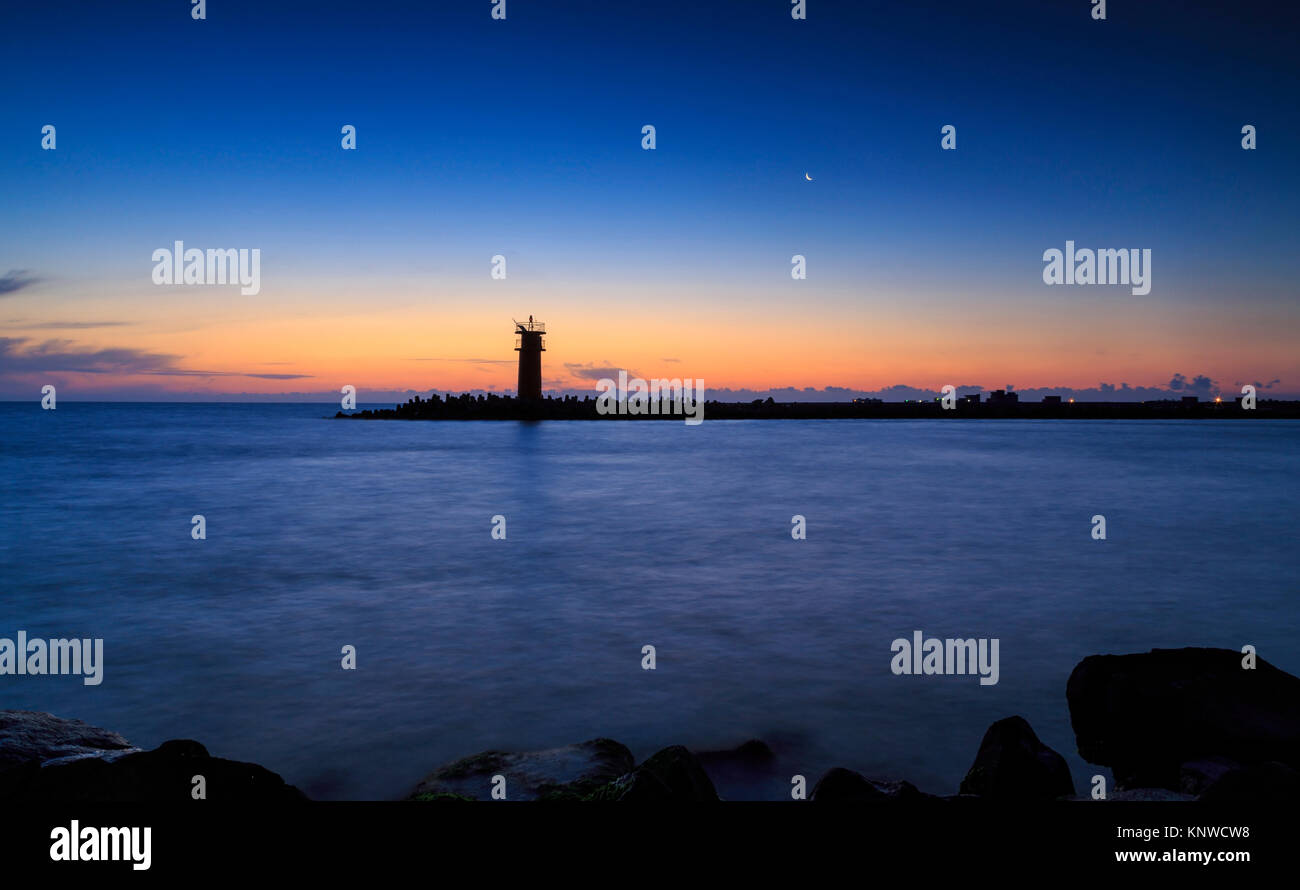Sunrise over lighthouse with moon on the sky Stock Photo - Alamy