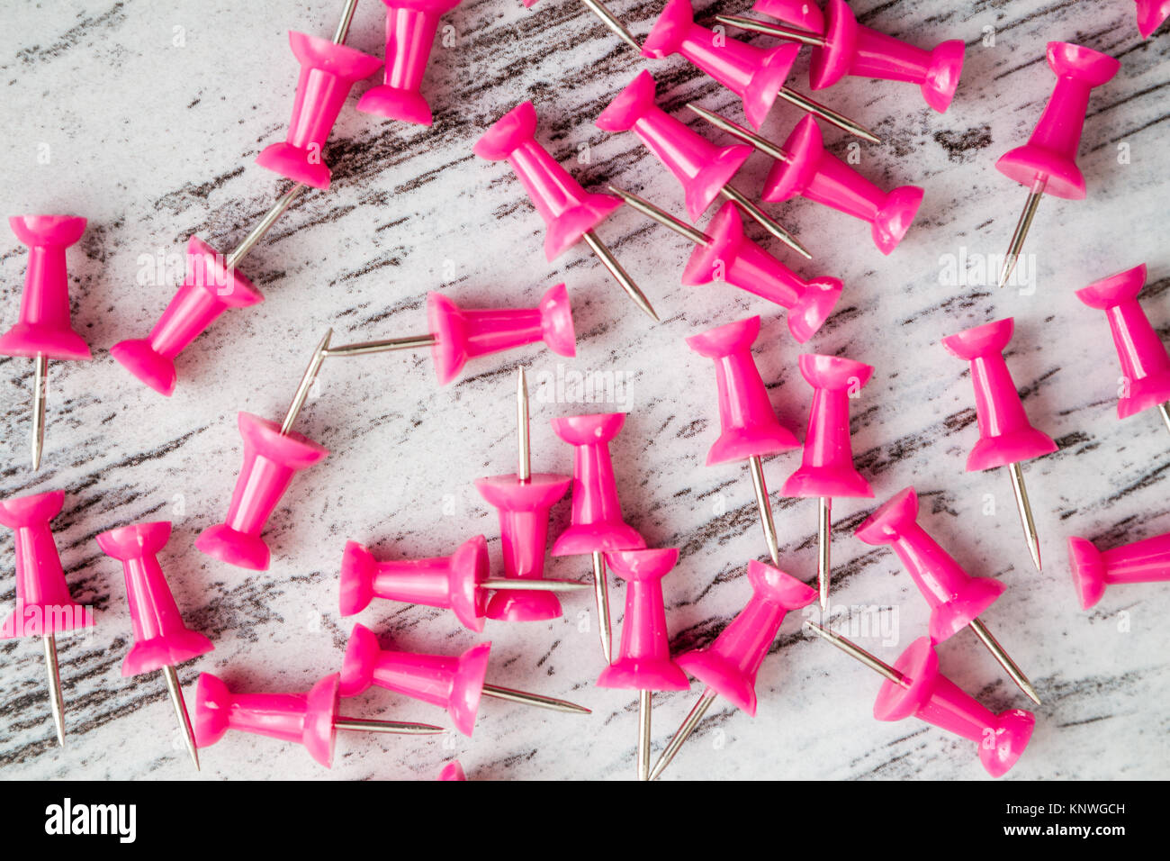 Pink colored paper pins dispersed on white background Stock Photo - Alamy