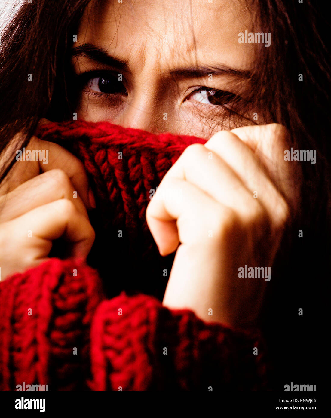 young brunette gloomy woman in sweater all over her face, messed hair ...