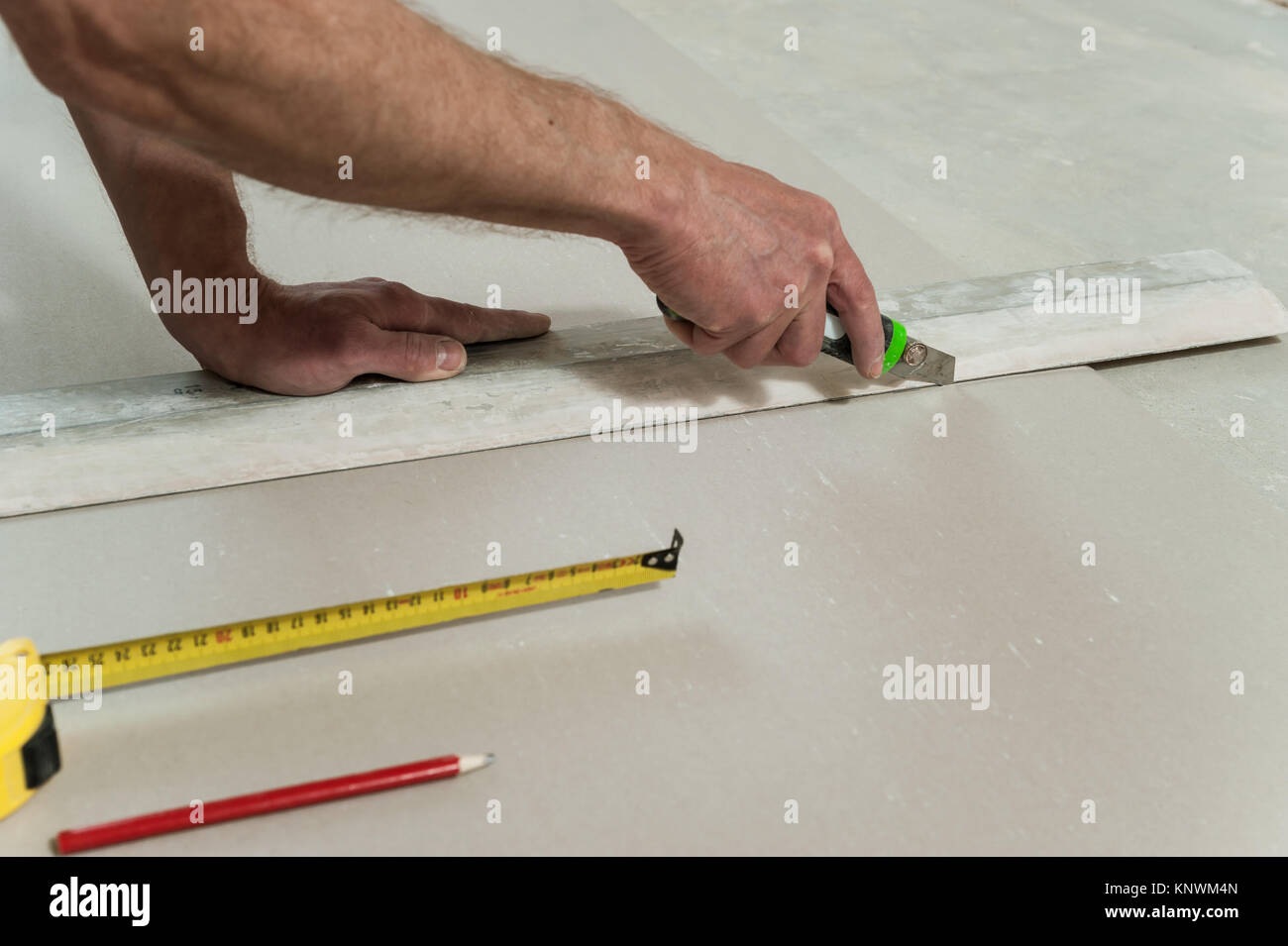 Man cuts off a piece of drywall with a knife and a ruler Stock Photo ...