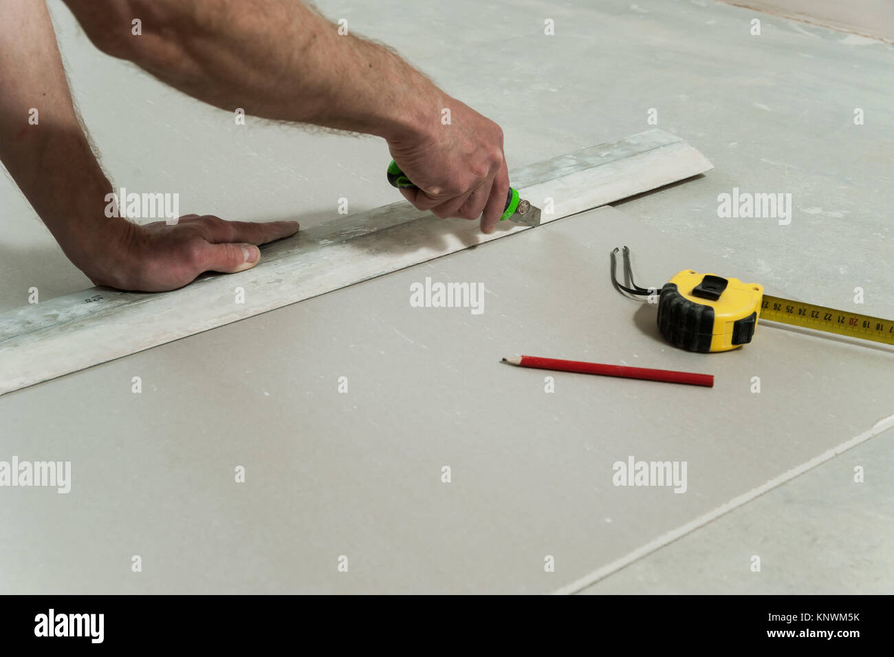 Man cuts off a piece of drywall with a knife and a ruler Stock Photo ...