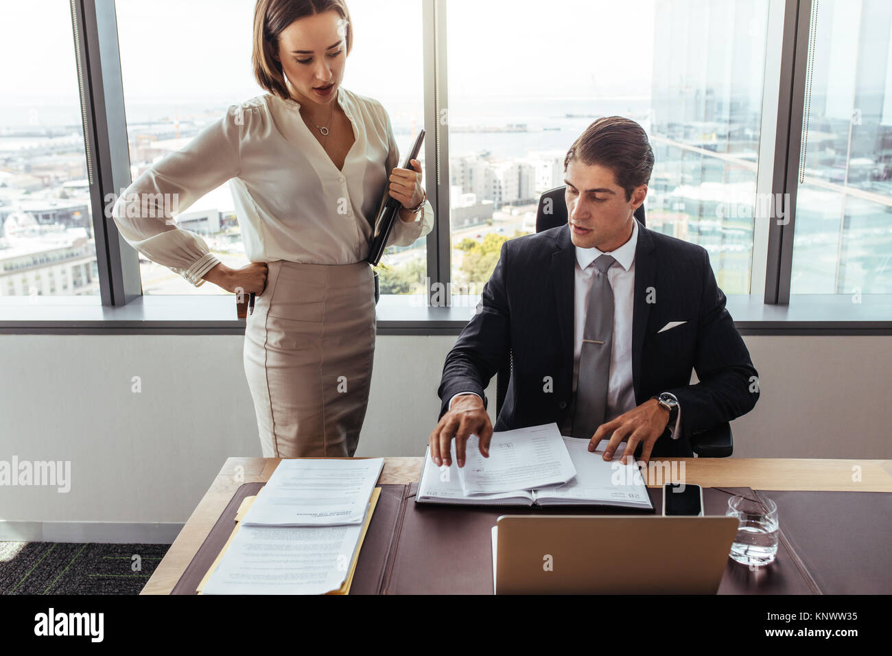 Two business people discussing contract documents together in office ...