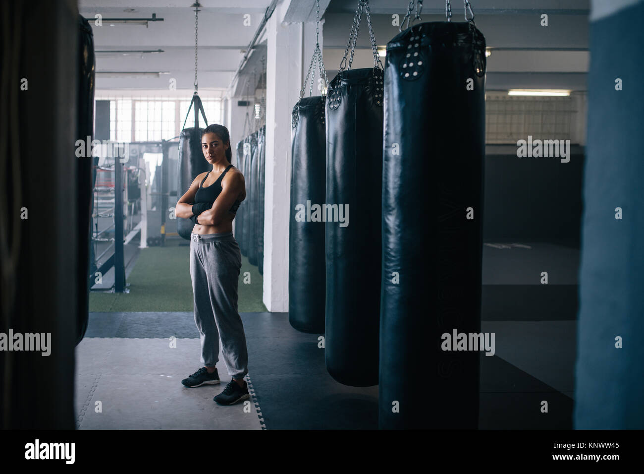Female boxer standing inside a boxing studio with her hands folded ...