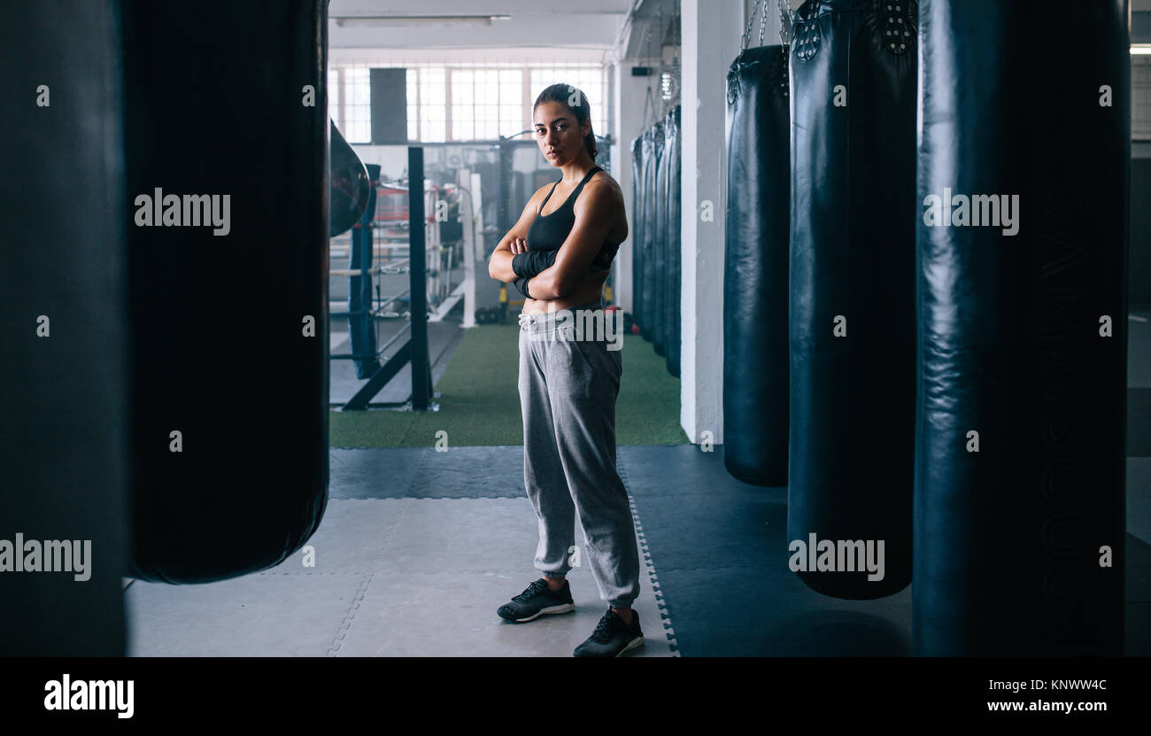 Woman standing in a boxing training centre with punching bags all ...