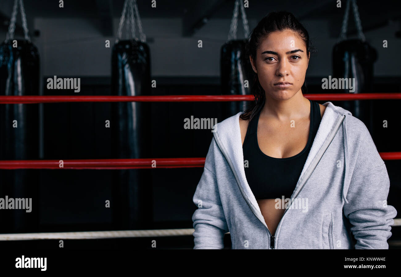 Serious looking female boxer standing inside a boxing ring wearing a ...