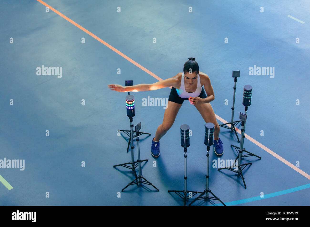 Fit young woman doing hand eye reaction training with lights sensors ...