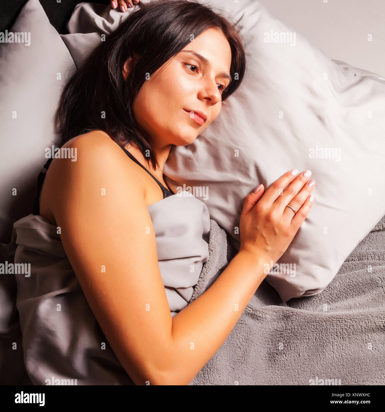 Woman with a smile face lying in bed on dark background Stock Photo - Alamy