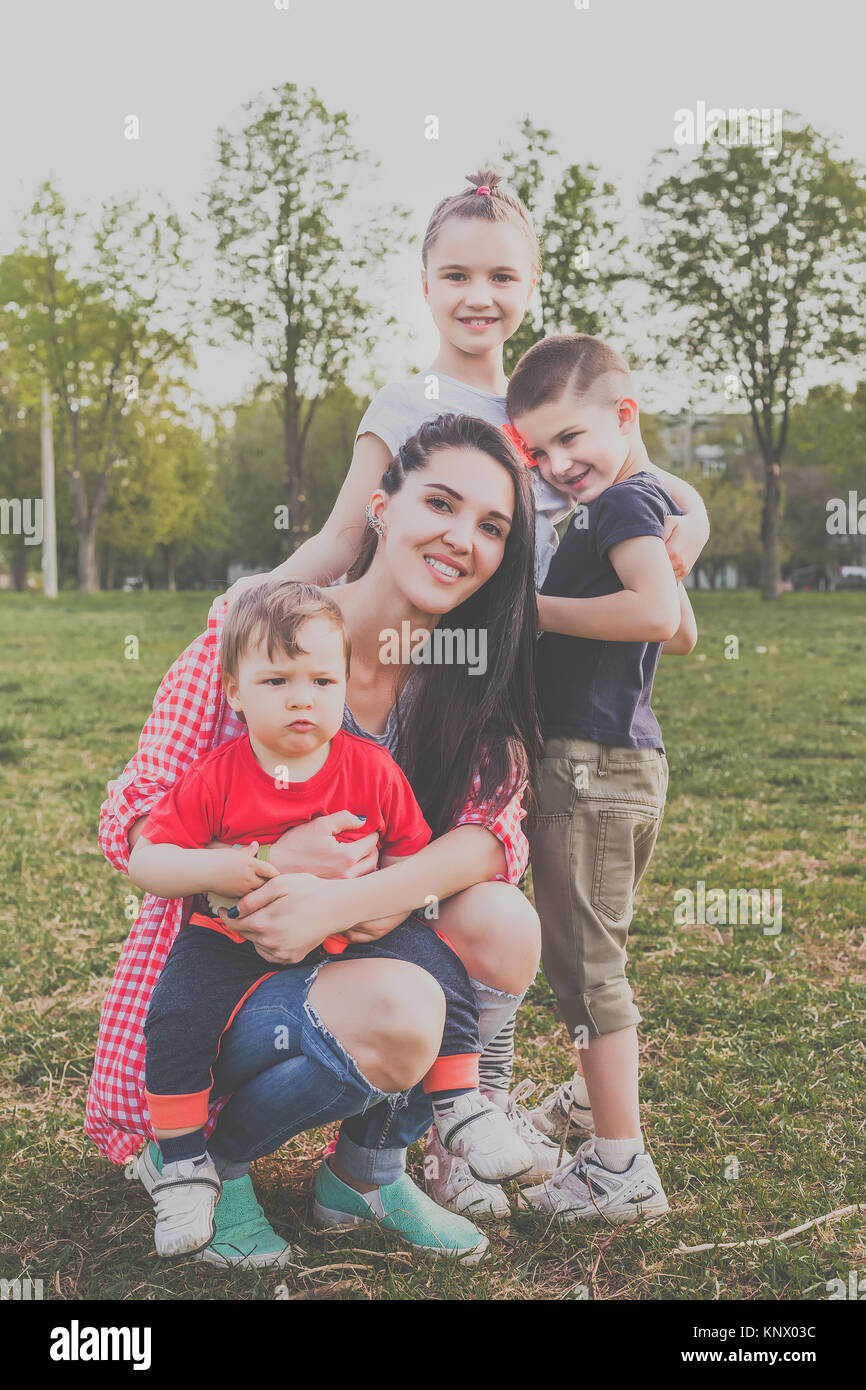 mother with three kids in the green meadow. hipster style. casual ...