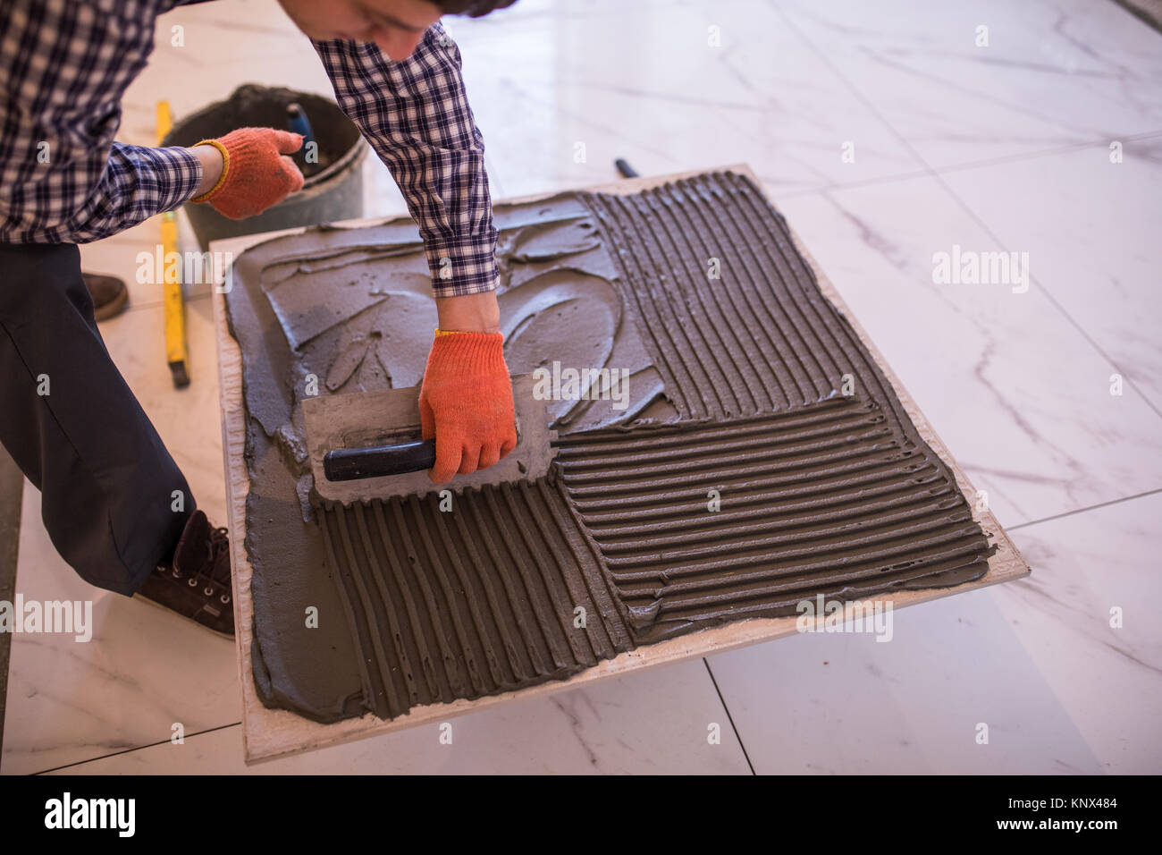 The worker's hand is putting tiles adhesive to the wall with the ...