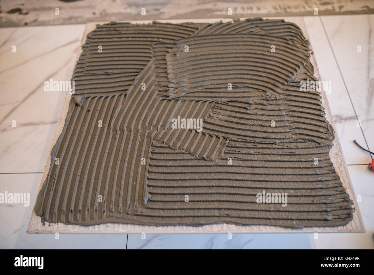 man hand troweling adhesive for ceramic tile flooring Stock Photo - Alamy